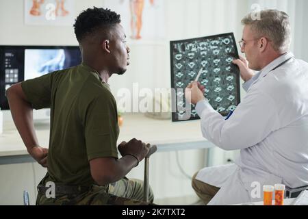 Doctor showing spine discs MRI image to military man and explaining ...