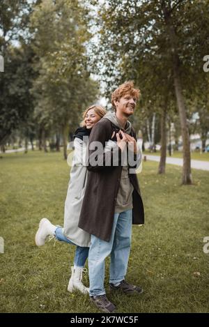full length of positive redhead man and cheerful woman holding coffee ...