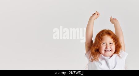Thrilled little girl, kid shouting in rejoice and raising hands up ...