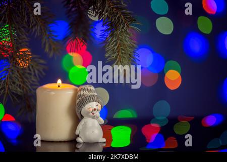 Jolly snowman toy and burning candle on sparkling and fabulous bokeh ...