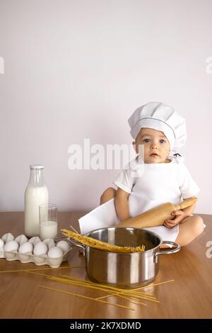 Kid boy in chef hat and apron cooking preparing meal. Little cook with ...