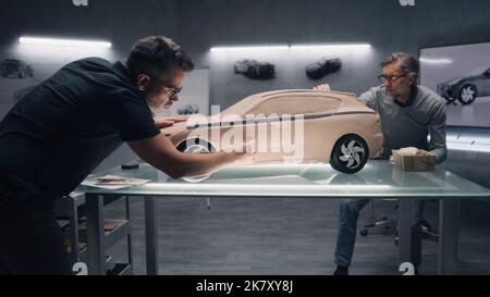 Two male automotive designers working on model of eco friendly electric ...