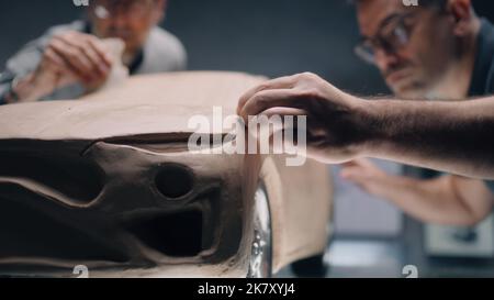 Two male automotive designers creating futuristic plasticine clay ...