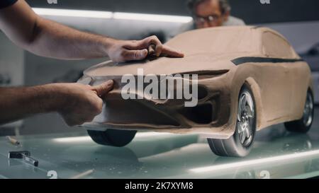 Two male automotive designers creating futuristic plasticine clay ...