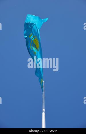 A giant, blue Kazakh flag, proudly flying on a tall flagpole in Central ...