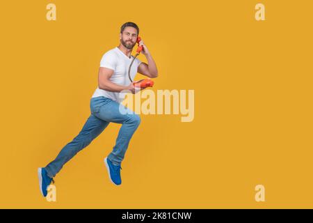 man running with telephone in midair. man call isolated on yellow ...