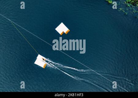 Aerial wakeboarding. Top view of awakeboard rider in wake cable park ...