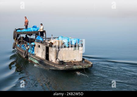 A garbage disposal barge for Nile cruise boats with men offloading blue ...