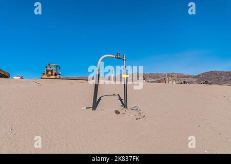 A vertical methane wellhead framing a distant vertical methane wellhead ...
