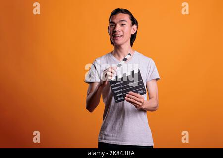 Young asian cameraman assistant slapping film making clapperboard ...