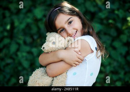 Teddy loves to cuddle. a little girl standing outside with her teddybear Stock Photo - Alamy