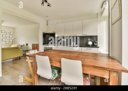 Table with chairs located near lounge area and kitchen in spacious room ...