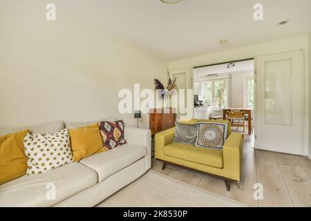 Table with chairs located near lounge area and kitchen in spacious room ...