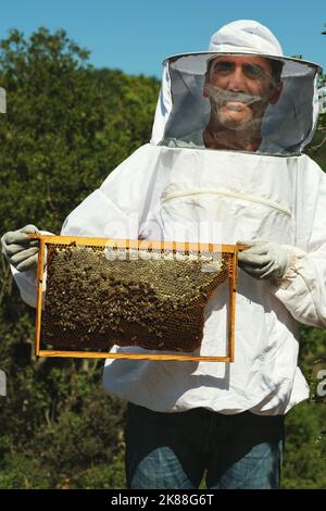 Portrait of a Turkish Beekeeper posing with a frame of honeycomb and ...