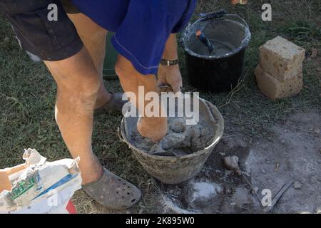 Image of an elderly bricklayer who with a board puts up some tuff ...