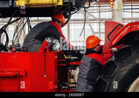 Industrial workers assembles agricultural tractor in workshop Stock ...