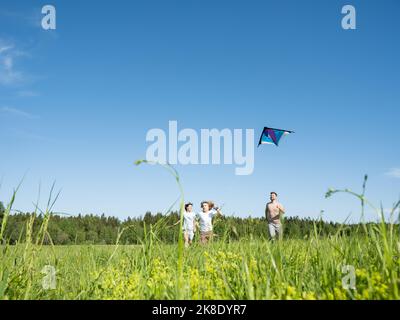 Happy family running through field with kite Stock Photo - Alamy