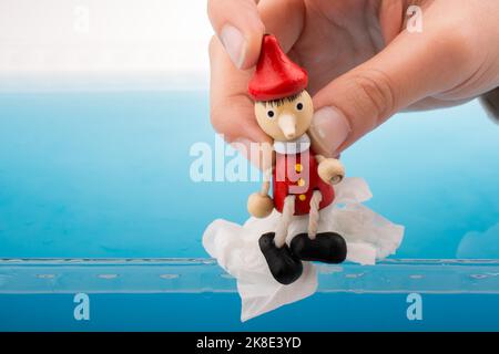 Hand holding wodden puppet Pinocchio on in blue water Stock Photo - Alamy