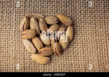 Pistachios form a heart shape on canvas background Stock Photo - Alamy
