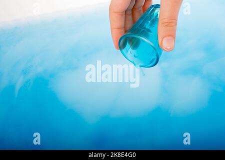 Water pouring down out of blue color glass in hand Stock Photo - Alamy