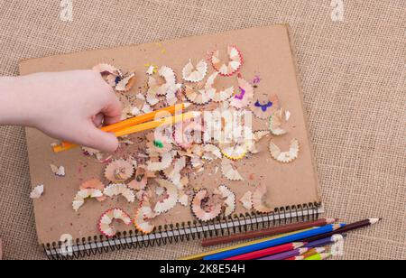 Hand holding Color Pencils over a notebook with pencil shavings Stock ...