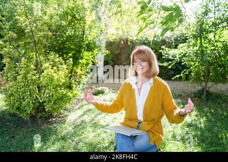 Smiling freelancer with eyes closed meditating on desk in home office ...