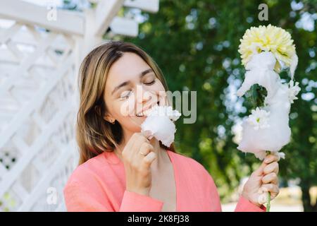 Happy woman eating cotton candy with flowers Stock Photo - Alamy