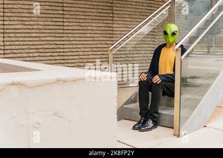 Man wearing alien mask sitting in front of STOP sign on road Stock ...