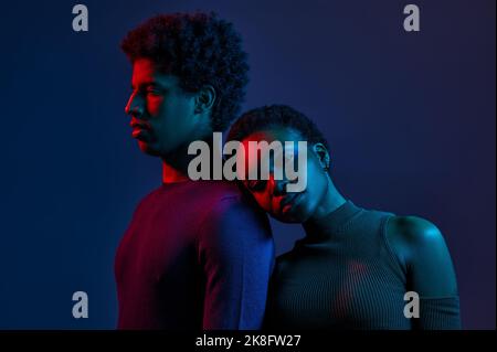Woman leaned on man shoulder, young confident people in neon light over ...