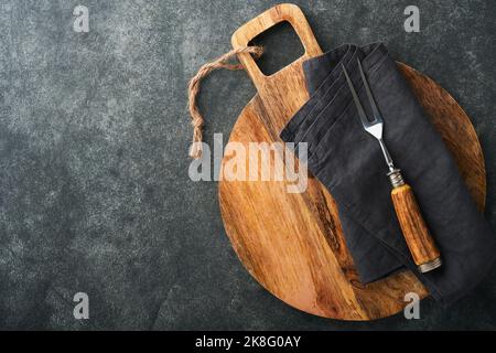BBQ and meat fork, rosemary leaves and spices on dark stone background ...
