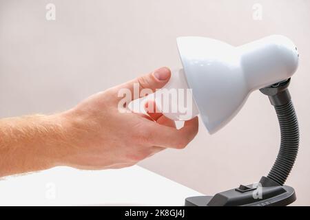 The man changes the lamp. Energy-saving lamp. Replacement of an energy ...