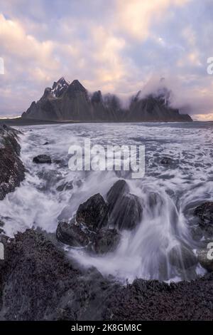 Picturesque scenery of waving sea washing rough shore near high snowy ...