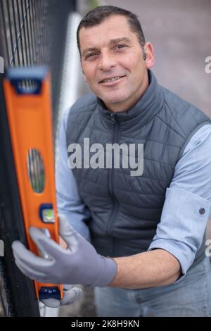 worker installing metal fence and checking with spirit level Stock ...