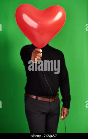 Handsome man with heart-shaped balloon on light background. Valentine's ...