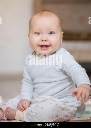 Baby girl with excited and amused expression lies in suitcase with ...
