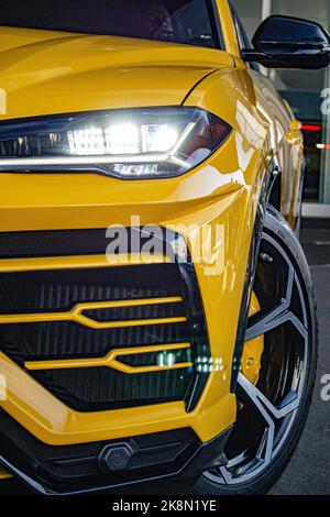 a vertical of Yellow Lamborghini Urus front view with headlights on ...