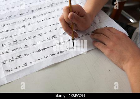 The sheet of paper with Chinese characters and hand with pen, the ...