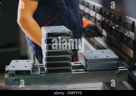 A factory worker arranges metal parts on top of each other, close-up ...