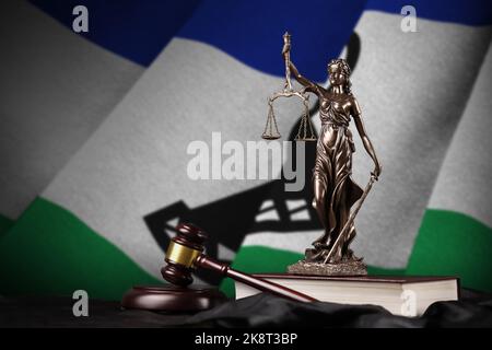 Lesotho flag with statue of lady justice and judicial scales in dark ...