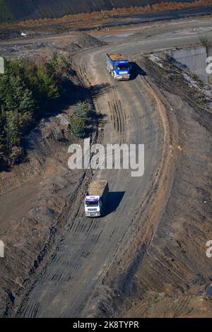 Large trucks transport excavated earth and rocks for highway ...