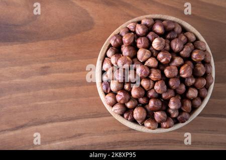 Wooden bowl full of hazelnuts on table background. Healthy eating ...