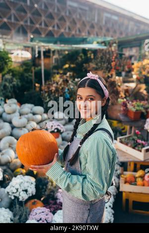 Farmer woman in a denim jumpsuit chooses ripe pumpkin Stock Photo - Alamy