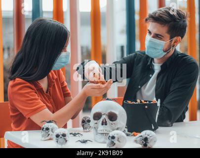 The people in masks talking about skull and bat halloween toy ...