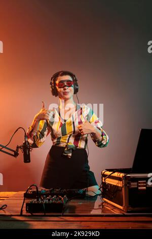 Woman performer showing thumbs up symbol and playing guitar, edgy ...