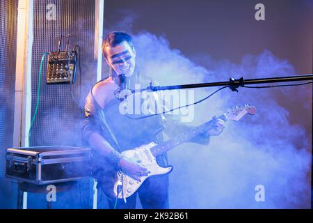 Stylish rocker doing live show singing heavy metal music with guitar ...