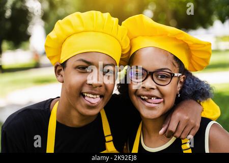 African children cooks in chefs hat and yellow uniforms grimacing and ...