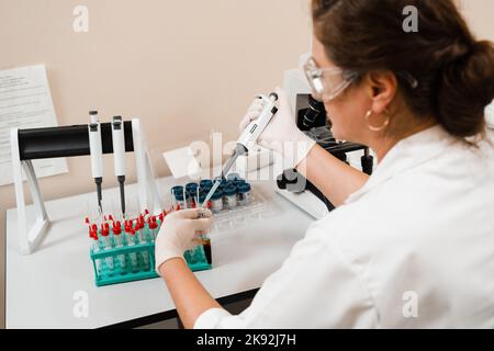 Laboratory assistant with microdoser in laboratory doing blood test ...