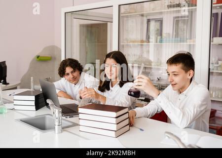 Pupils holding flasks with liquid for experiments in laboratory ...