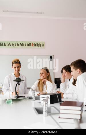 School chemistry teacher shows children flasks with liquids for ...