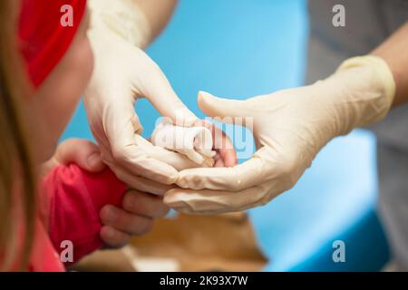 The hands of the doctor bandage the sore finger with a bandage of the ...